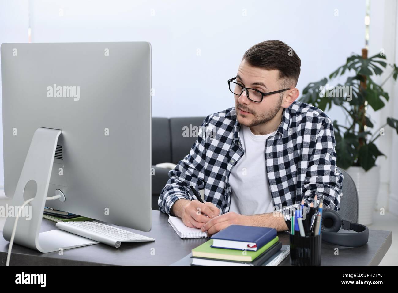 Young man using modern computer for studying at home. Distance learning ...