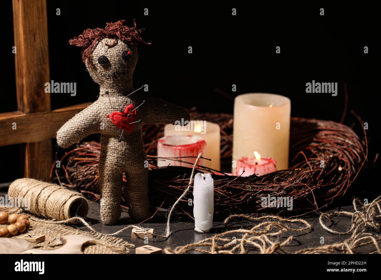 Voodoo doll with pins in heart and ceremonial items on black table ...