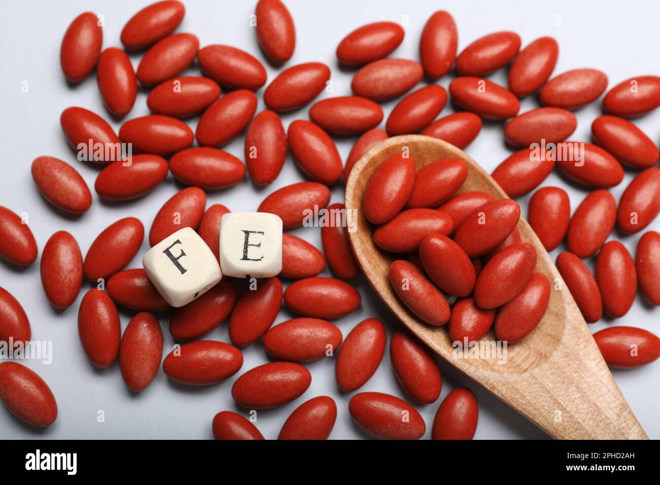 Wooden cubes with letters FE, spoon and red pills on white background ...