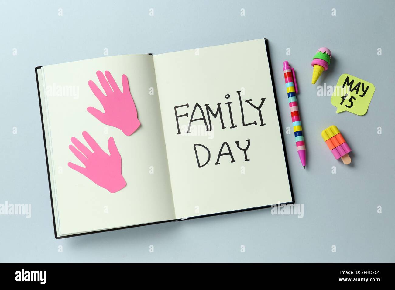 Notebook with text Family Day May, paper hand cutouts and stationery on ...