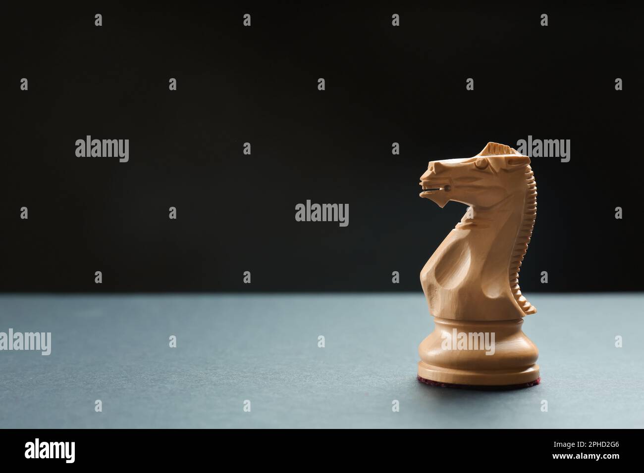 Wooden knight on table against dark background, space for text. Chess ...