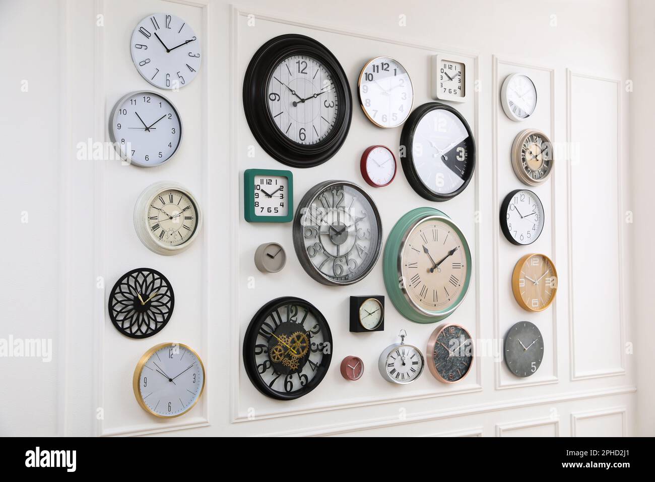 Collection of different clocks hanging on white wall Stock Photo - Alamy