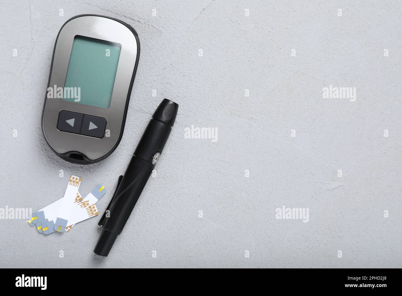 Glucometer, lancet pen and strips on grey table, flat lay with space ...