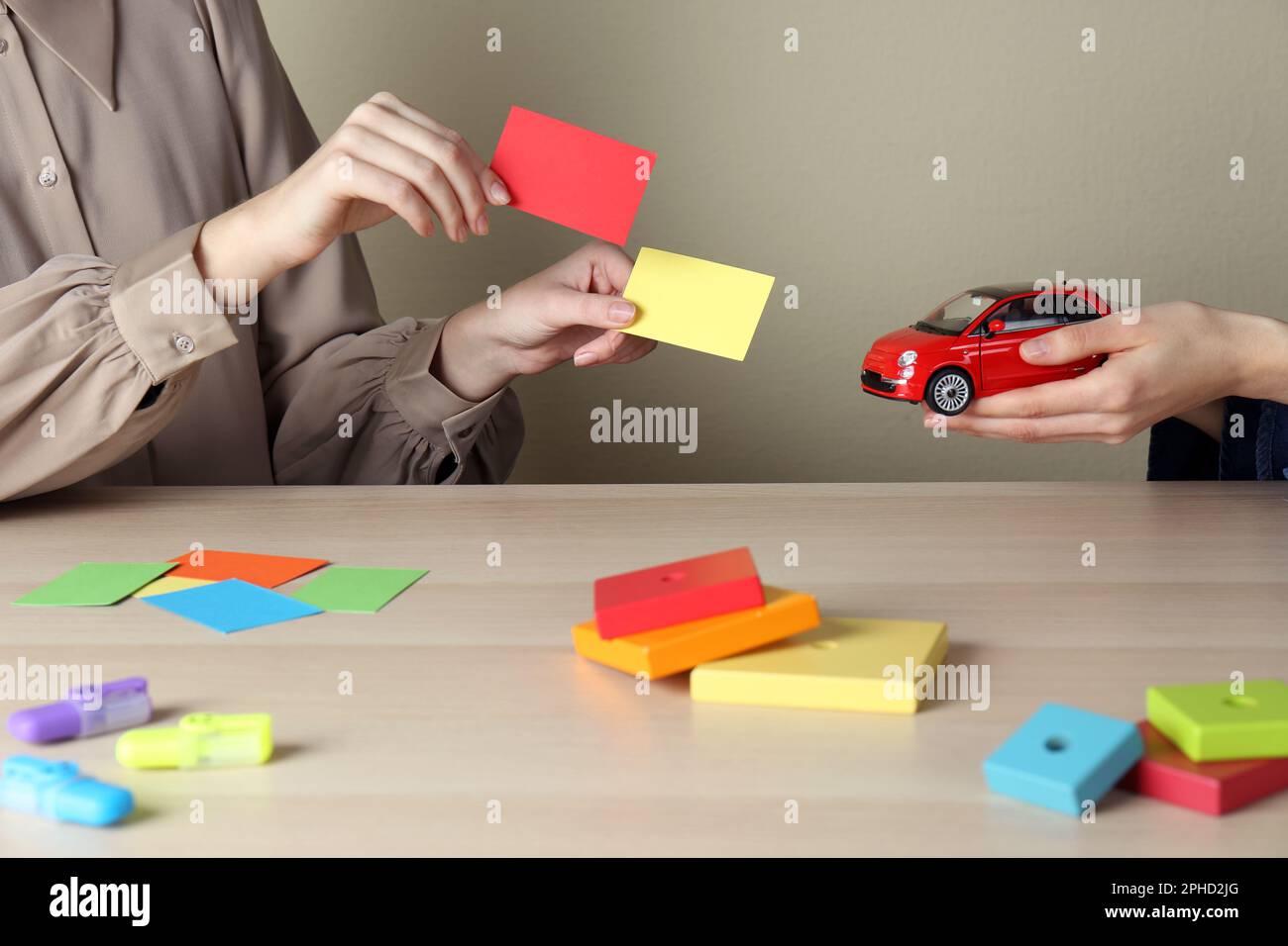 Women with toy car and color papers at wooden table indoors, closeup ...