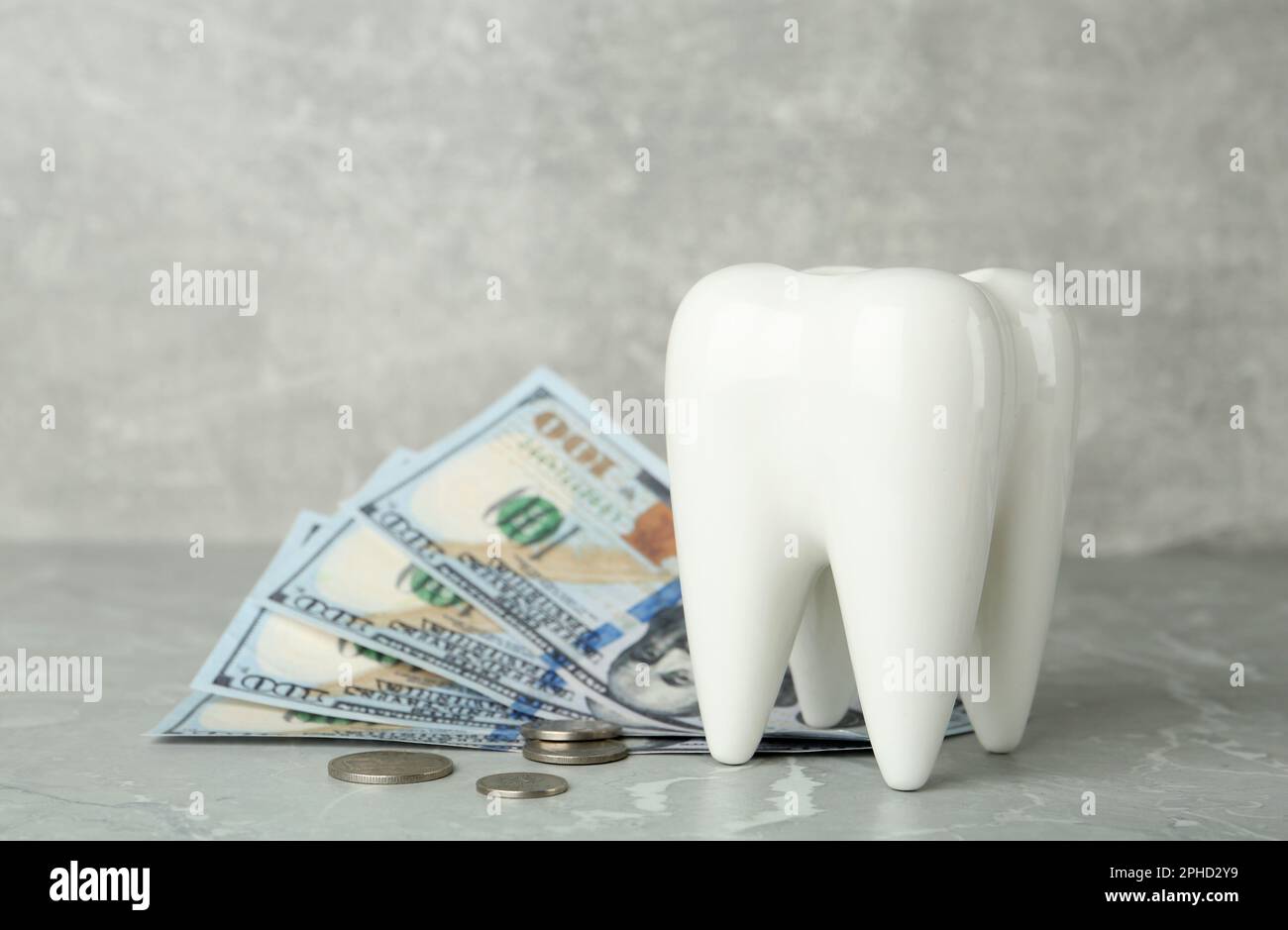Ceramic model of tooth and money on grey table. Expensive treatment ...