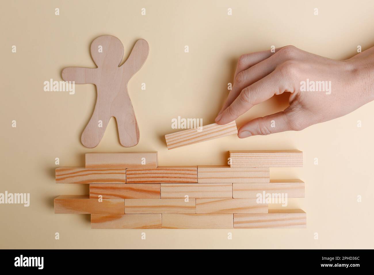 Woman putting wooden block to help human figure cross construction on ...