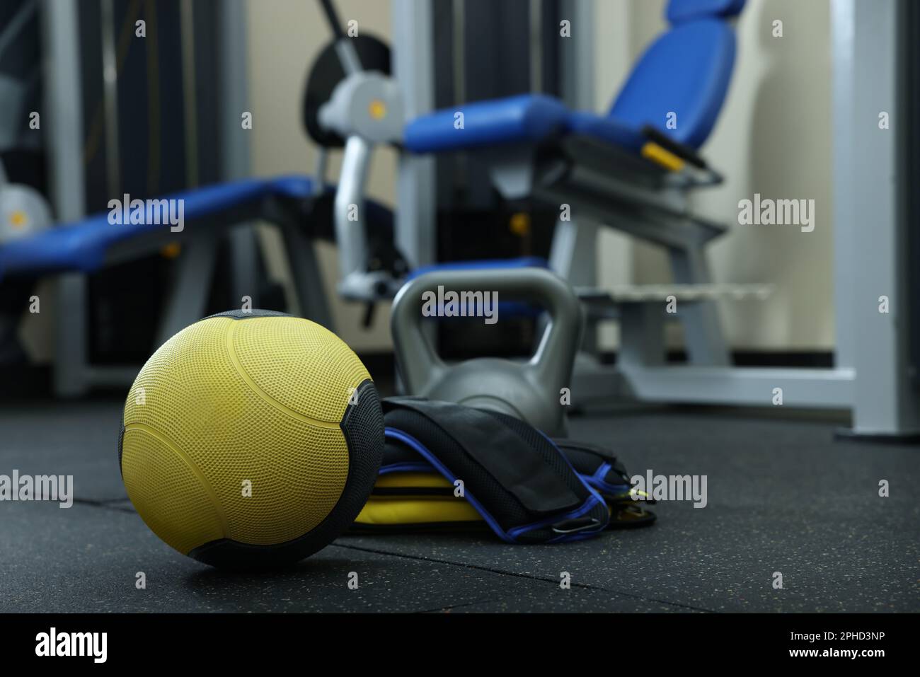 Yellow medicine ball, kettlebell and ankle weights on floor in gym ...
