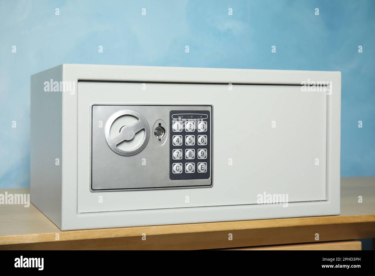 Closed steel safe on wooden table against light blue background Stock ...