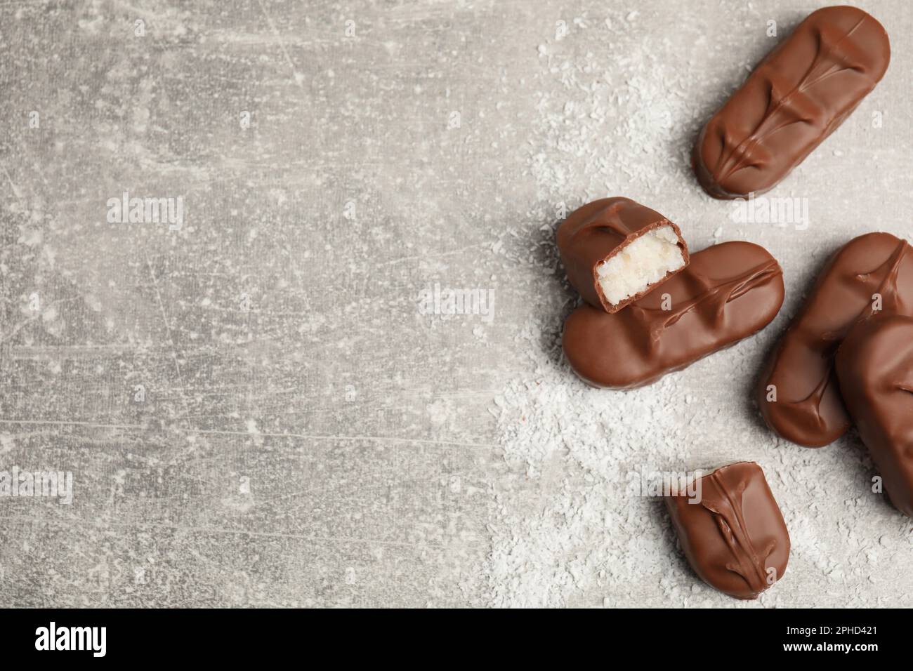 Delicious milk chocolate candy bars with coconut filling on grey table ...