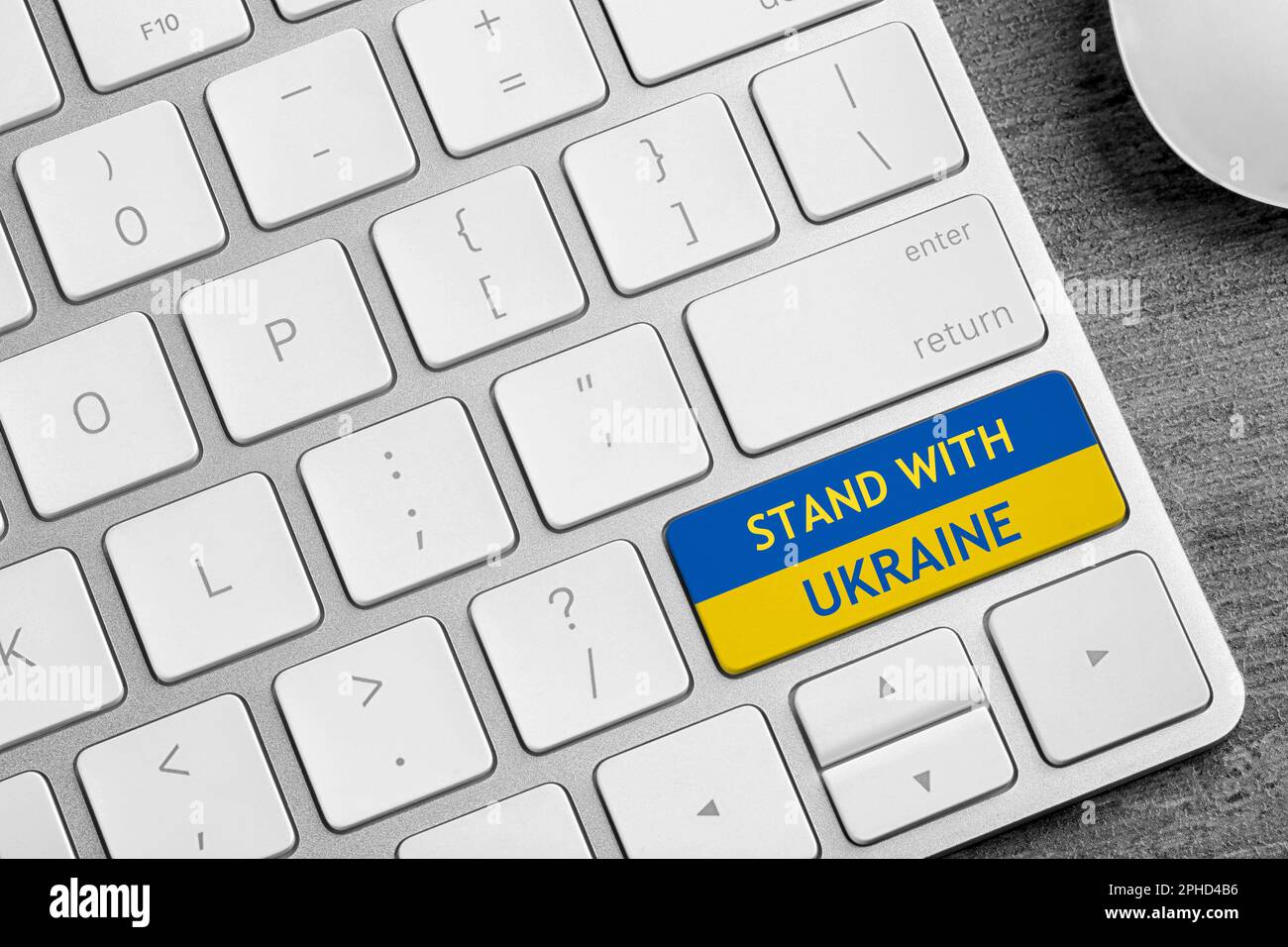 Button in colors of Ukrainian flag with phrase Stand With Ukraine on keyboard, closeup view ...