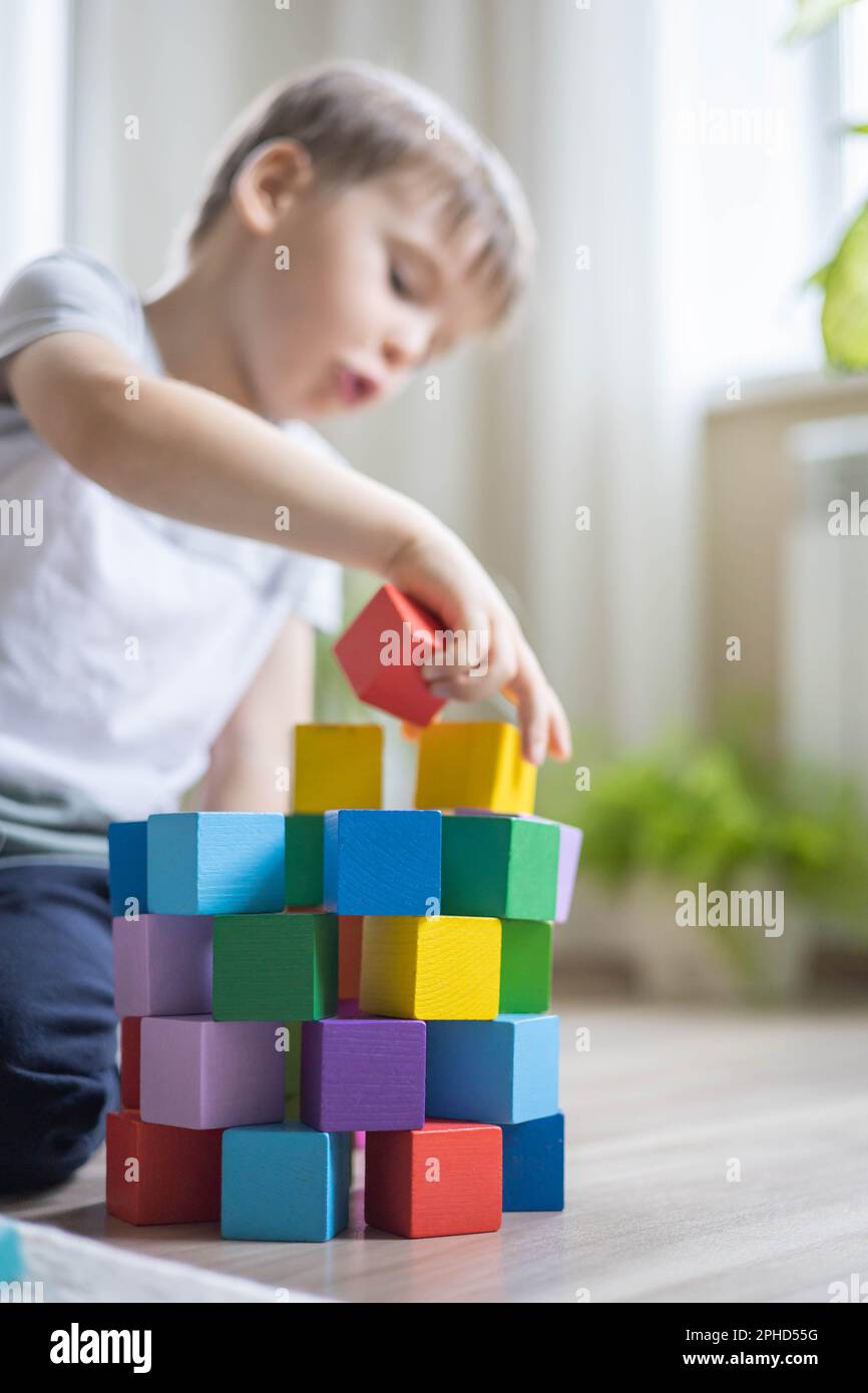 Confident male kid building fortress tower architecture wooden bricks ...