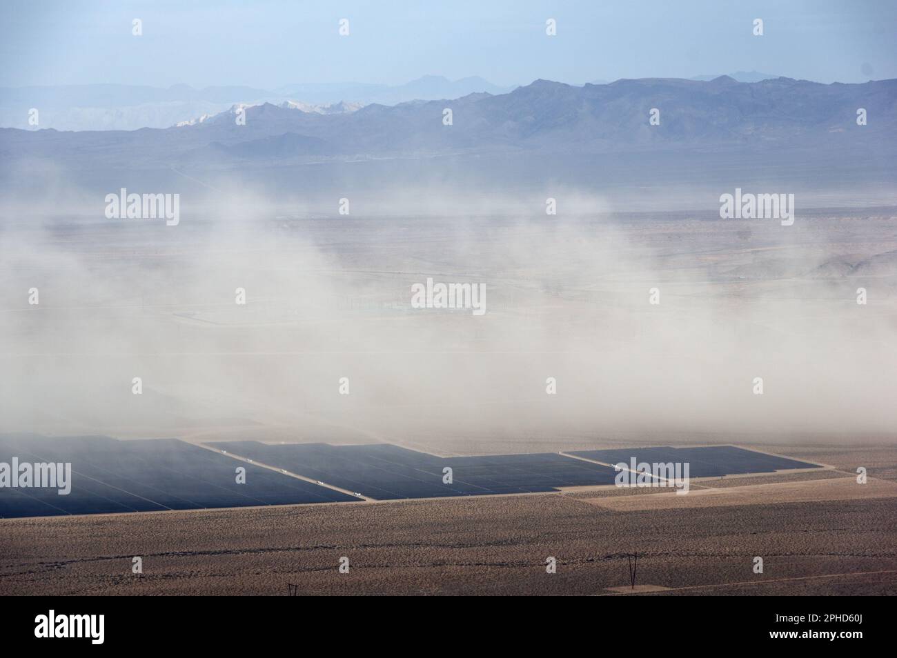 a dust storm blows over a distant grid scale solar electric power plant ...