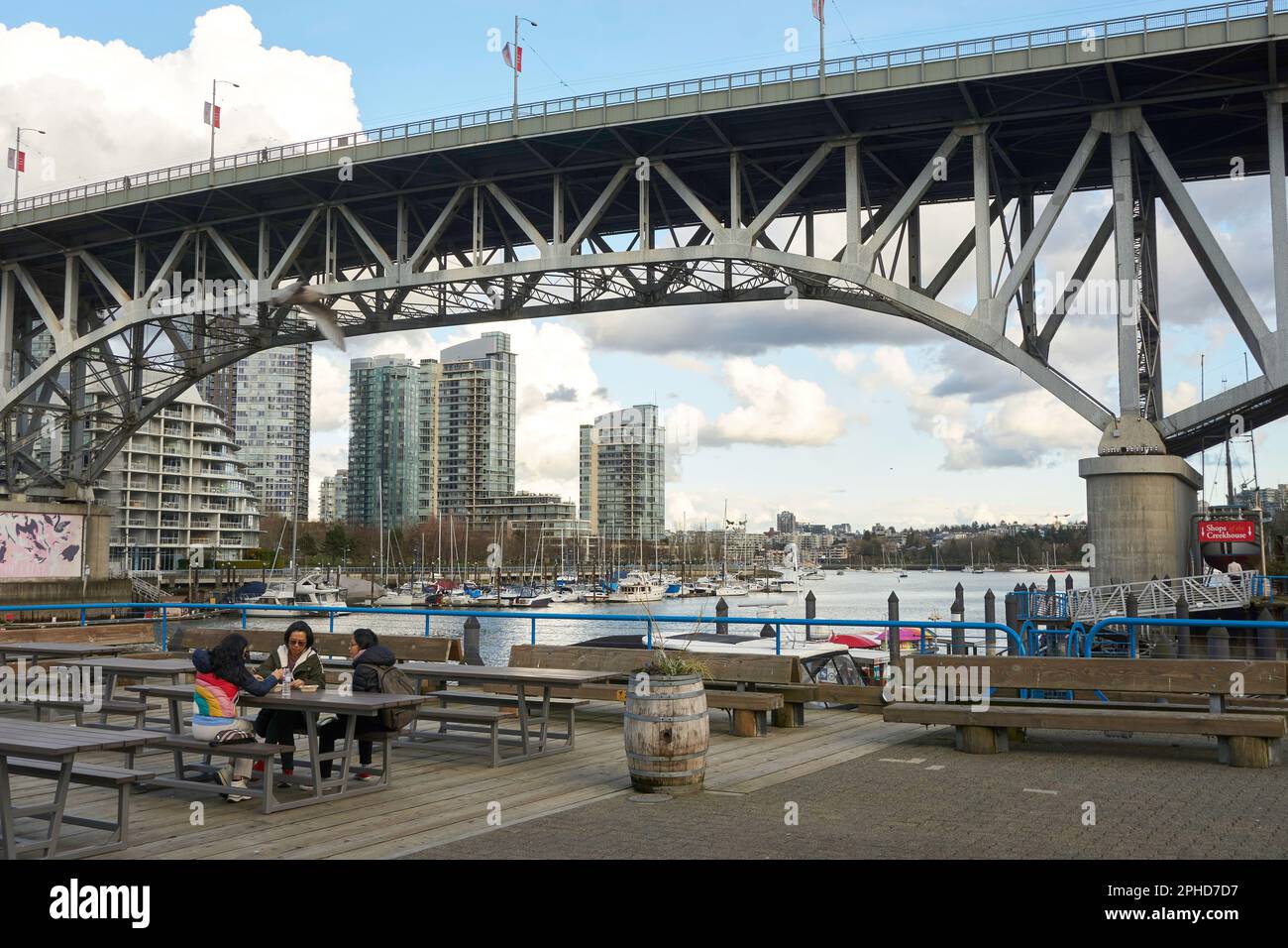 People eating outdoors at a picnic table with view of Granville Bridge ...