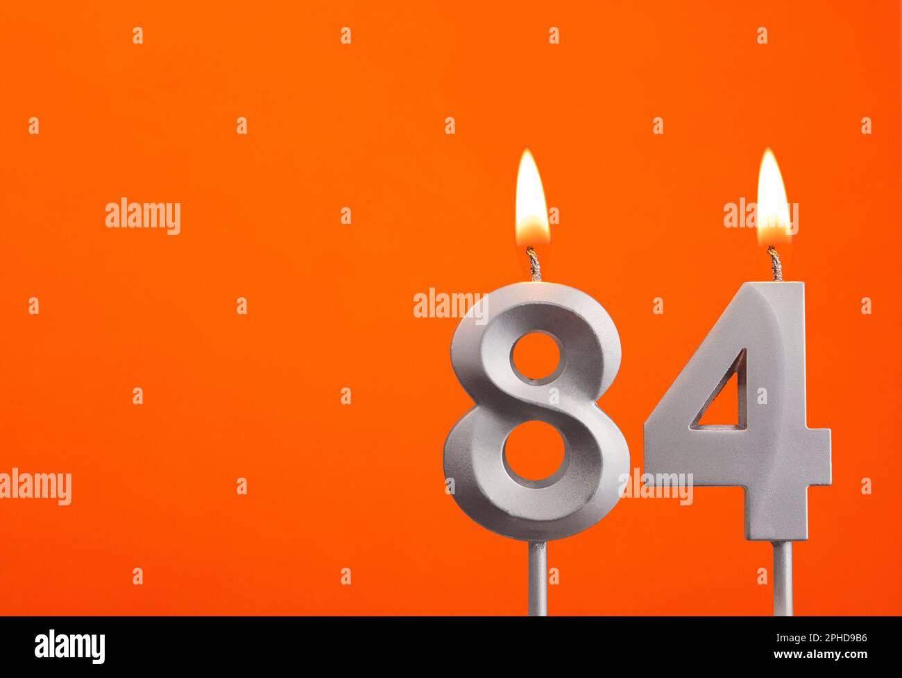 Candle number 84 - Birthday in orange background Stock Photo - Alamy