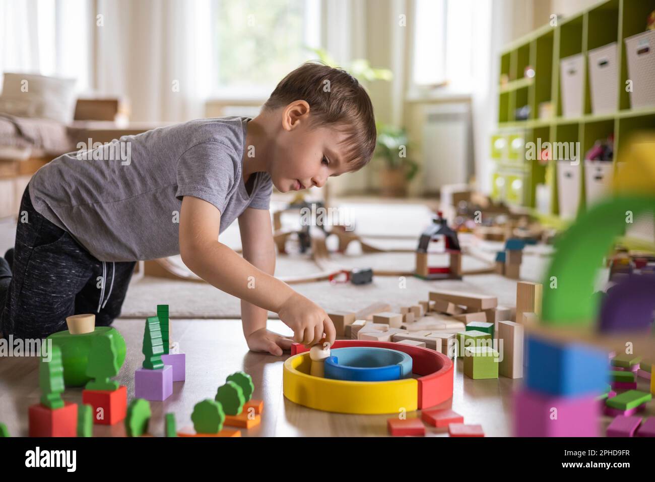 Confident male kid building fortress tower architecture wooden bricks ...