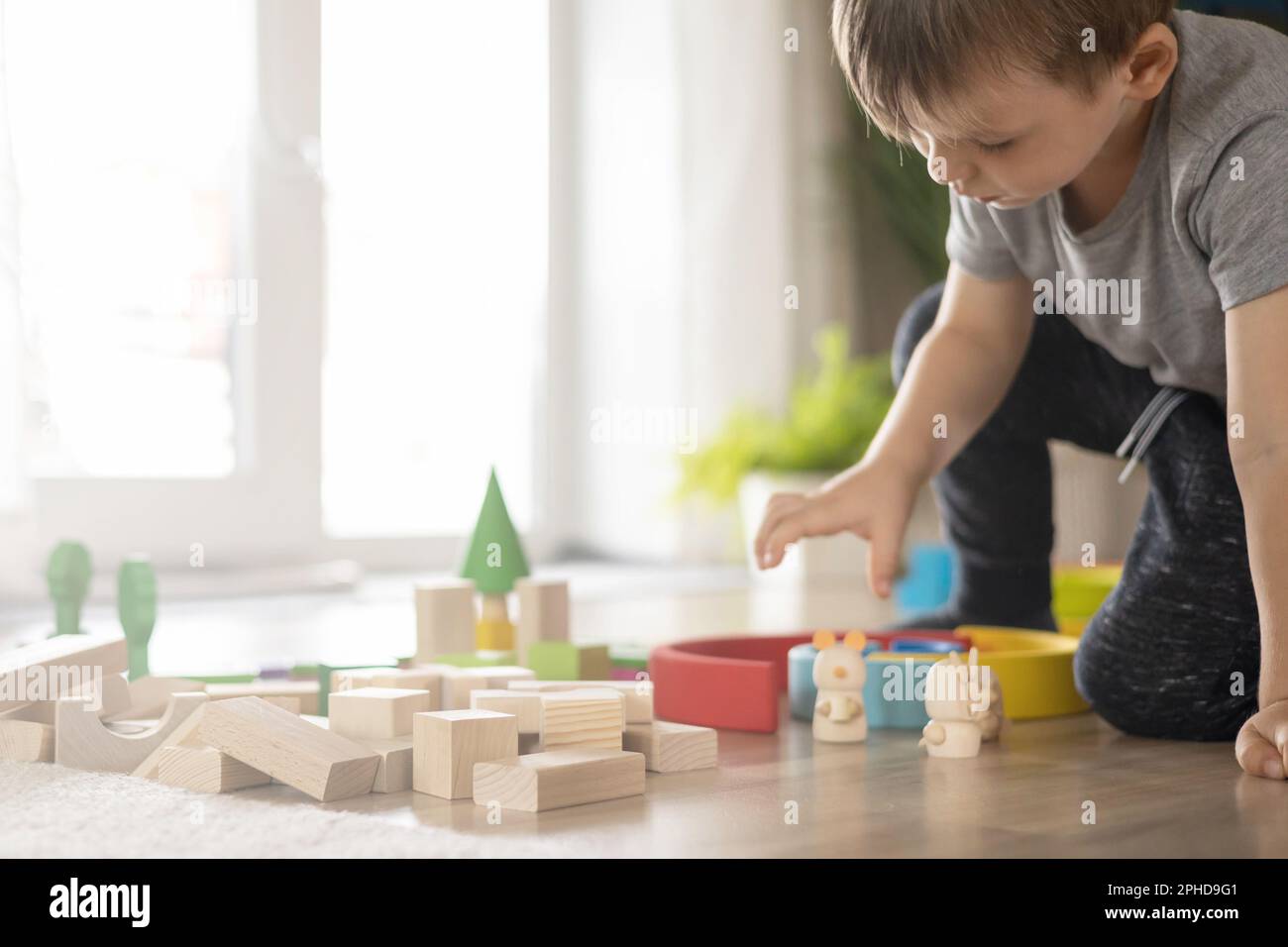 Confident male kid building fortress tower architecture wooden bricks ...