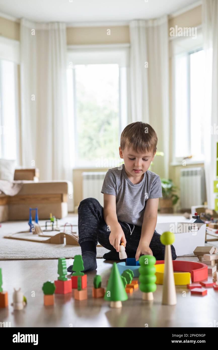 Confident male kid building fortress tower architecture wooden bricks ...