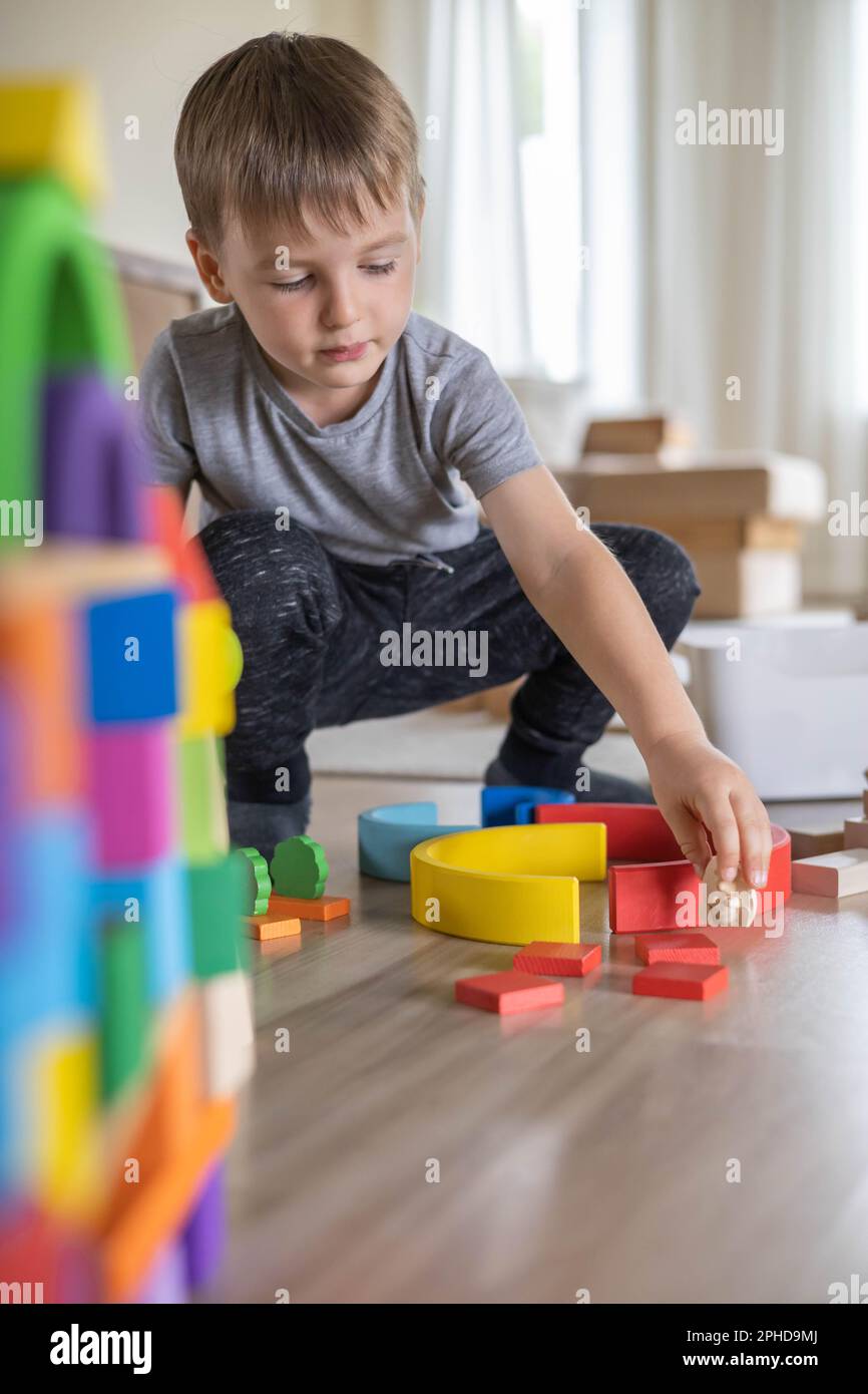 Confident male kid building fortress tower architecture wooden bricks ...