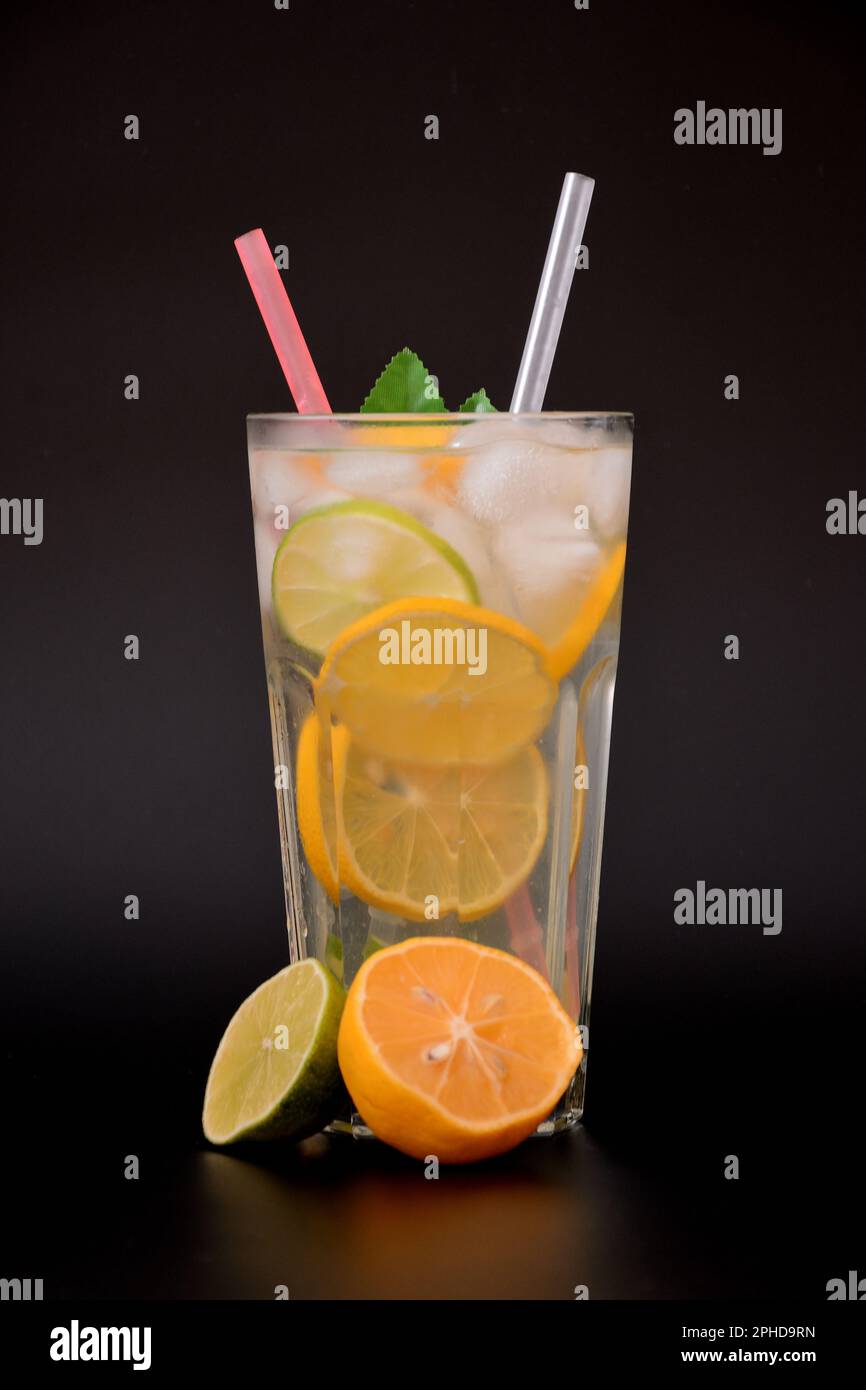 A tall glass of refreshing lemonade with ice on a black background ...