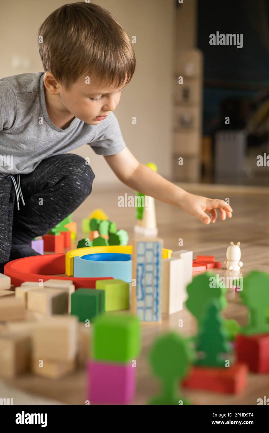 Confident male kid building fortress tower architecture wooden bricks ...