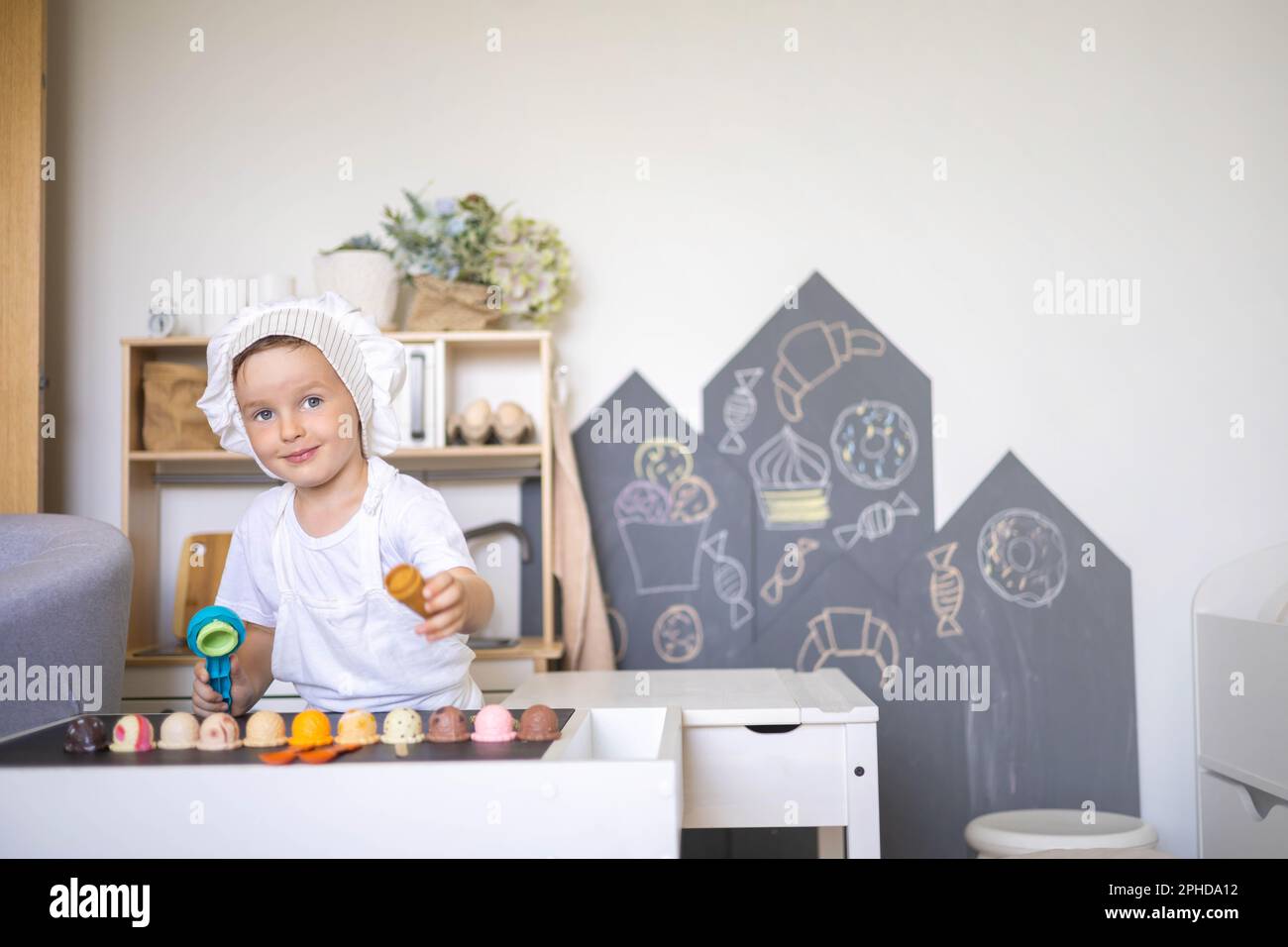 Cute male kid preparing toy food boiling vegetables on cooker at ...