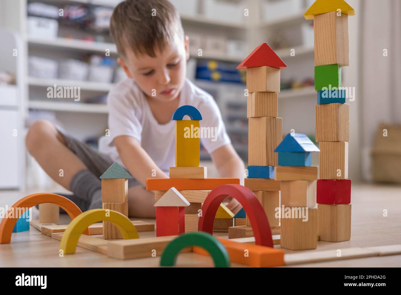 Confident male kid building fortress tower architecture wooden bricks ...