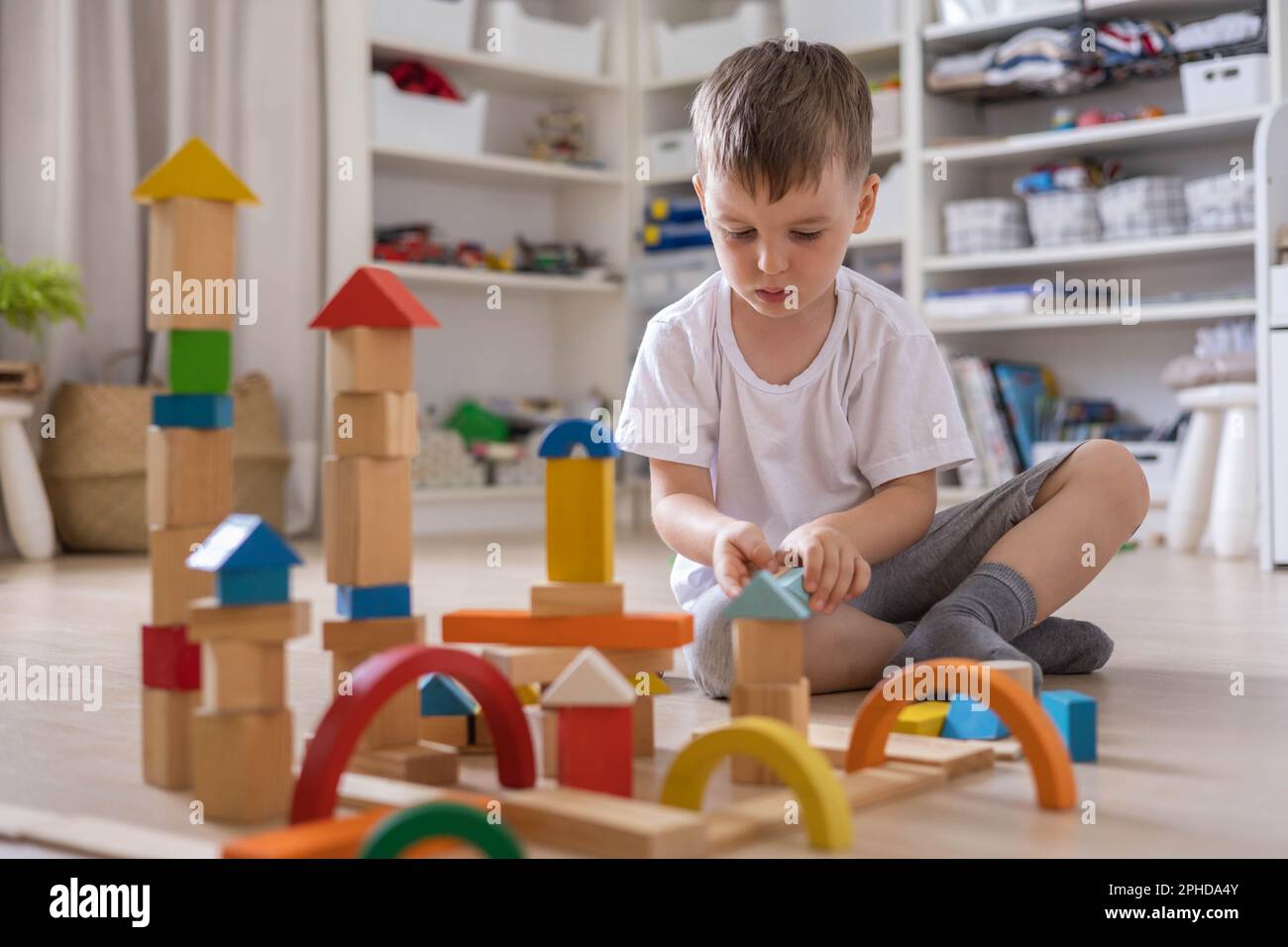 Confident male kid building fortress tower architecture wooden bricks ...