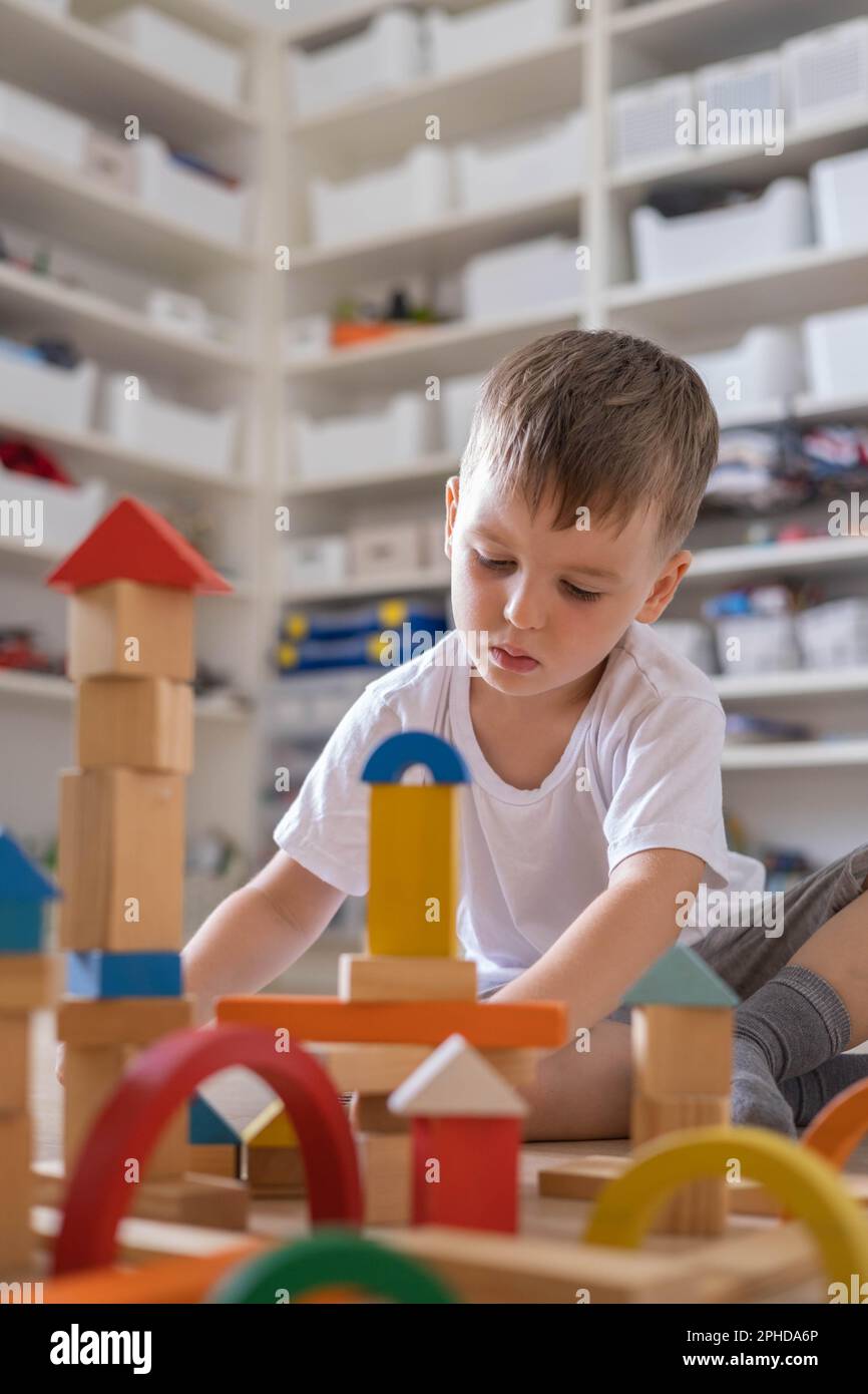 Confident male kid building fortress tower architecture wooden bricks ...