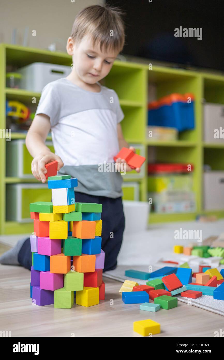 Confident male kid building fortress tower architecture wooden bricks ...