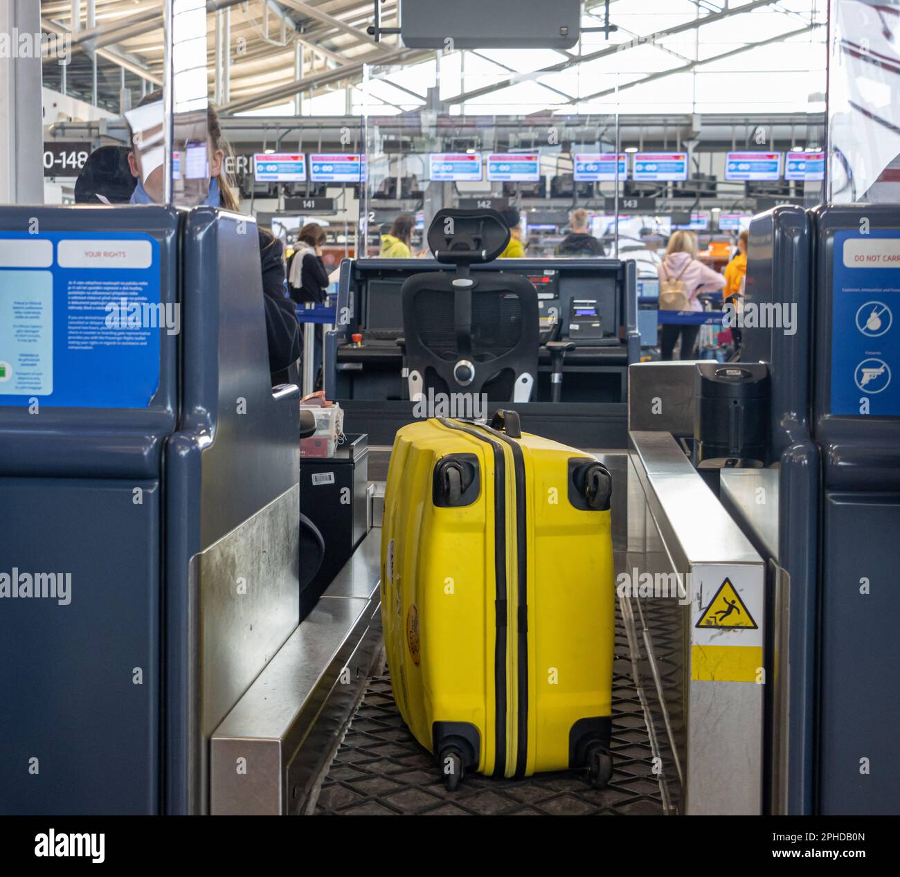 Passenger's yellow suitcase on a conveyor belt during check-in at an ...