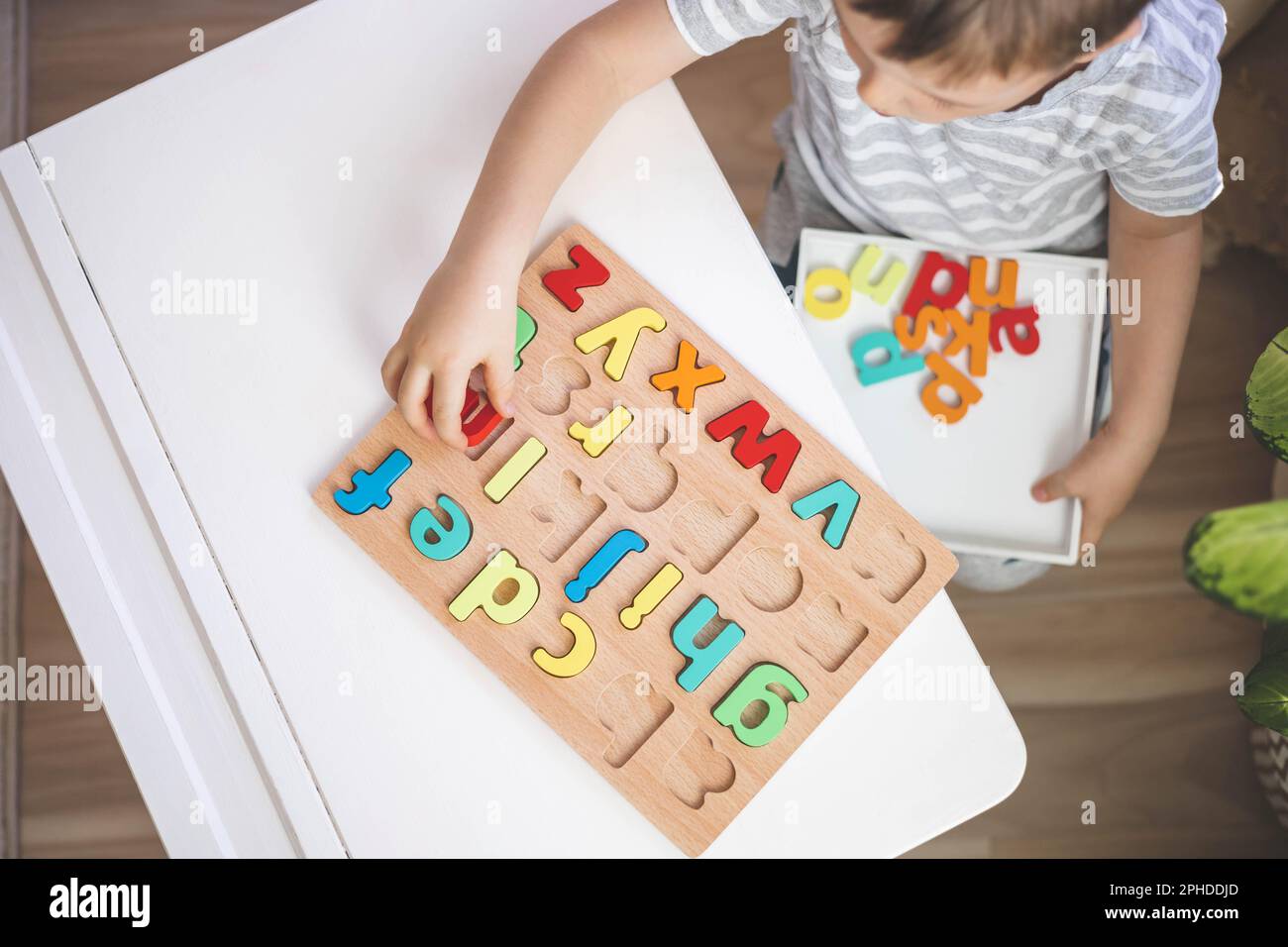 Childish hands holding alphabet wooden board with colored font letters ...
