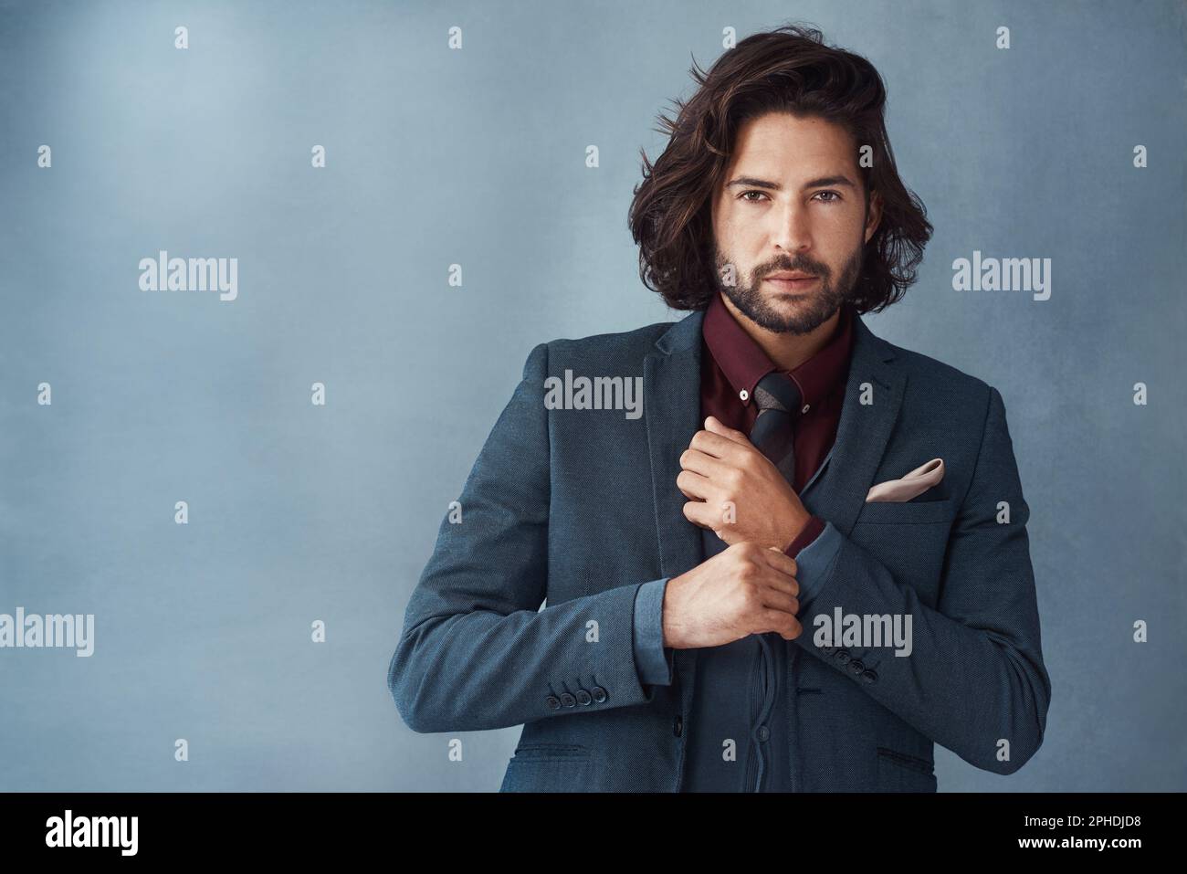 Real style from a real man. Studio shot of a handsome and dapper young man posing against a grey ...