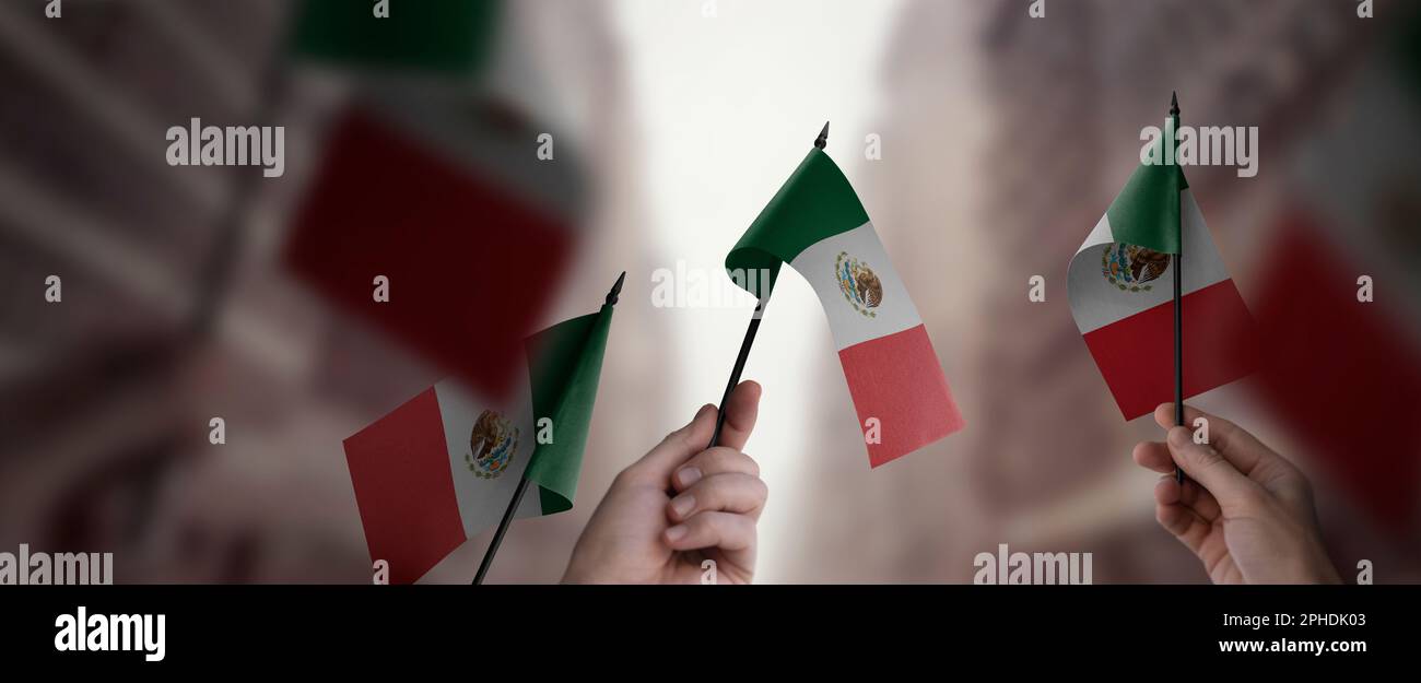 A group of people holding small flags of the Mexico in their hands ...