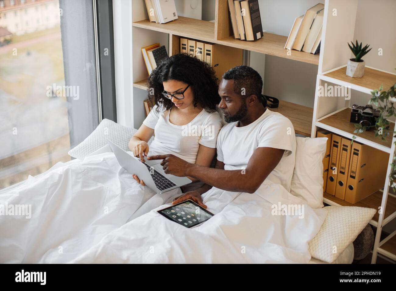 Cheerful amorous people accessing portable computer while spending time ...