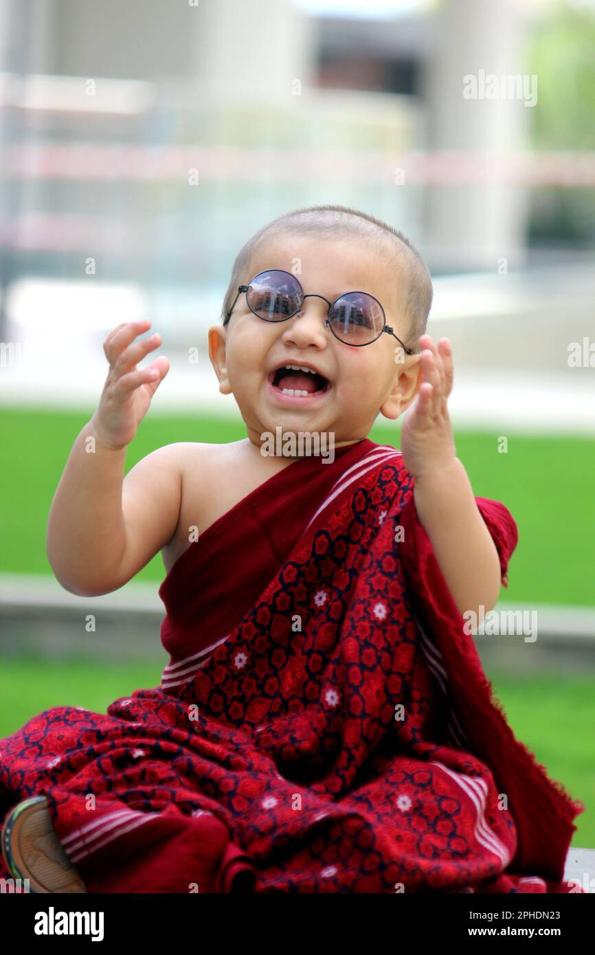 a cute bald baby boy is dressed up in Monk avatar, wearing a maroon ...