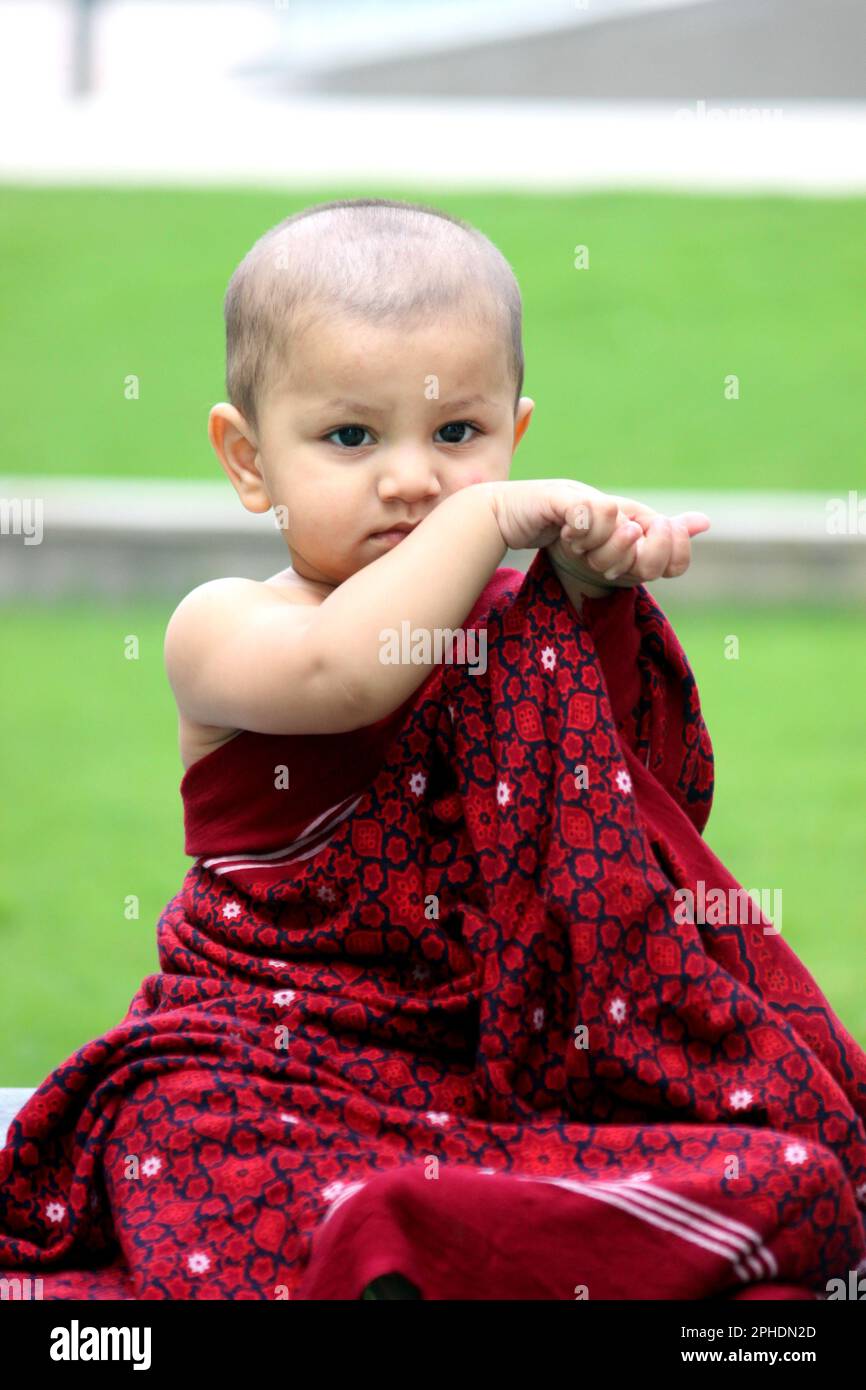 a cute bald baby boy is dressed up in Monk avatar, wearing a maroon ...