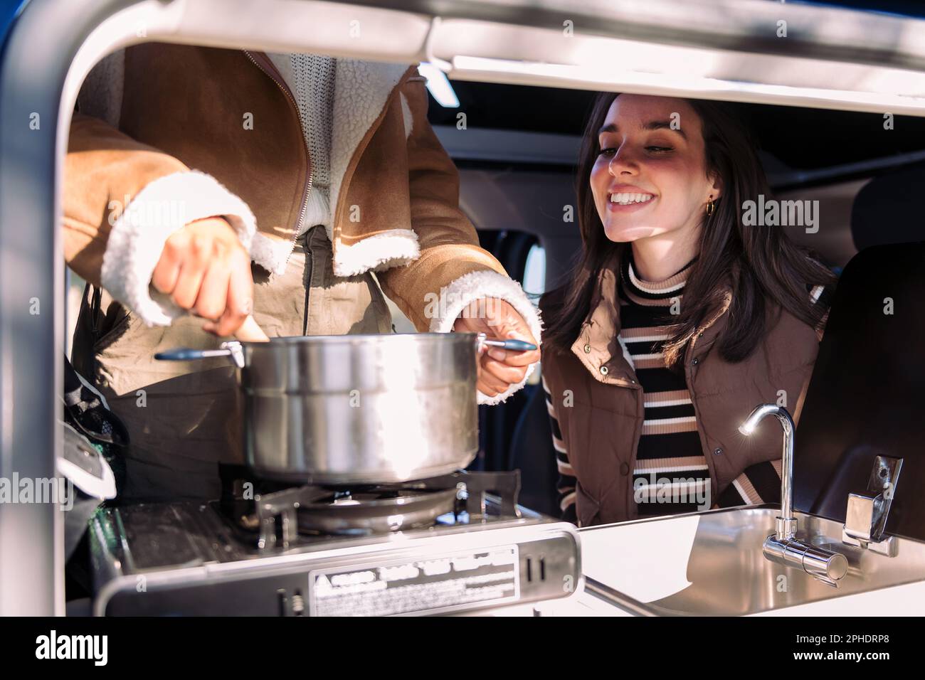friends in a road trip cooking in camper van Stock Photo - Alamy