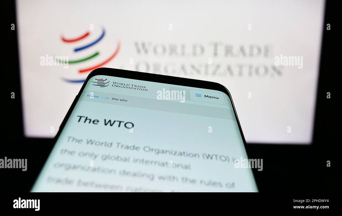 Smartphone with website of World Trade Organization (WTO) on screen in front of logo. Focus on ...