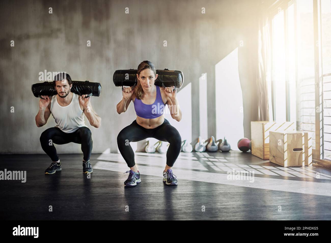 Push through together. two young people working out in the gym using ...