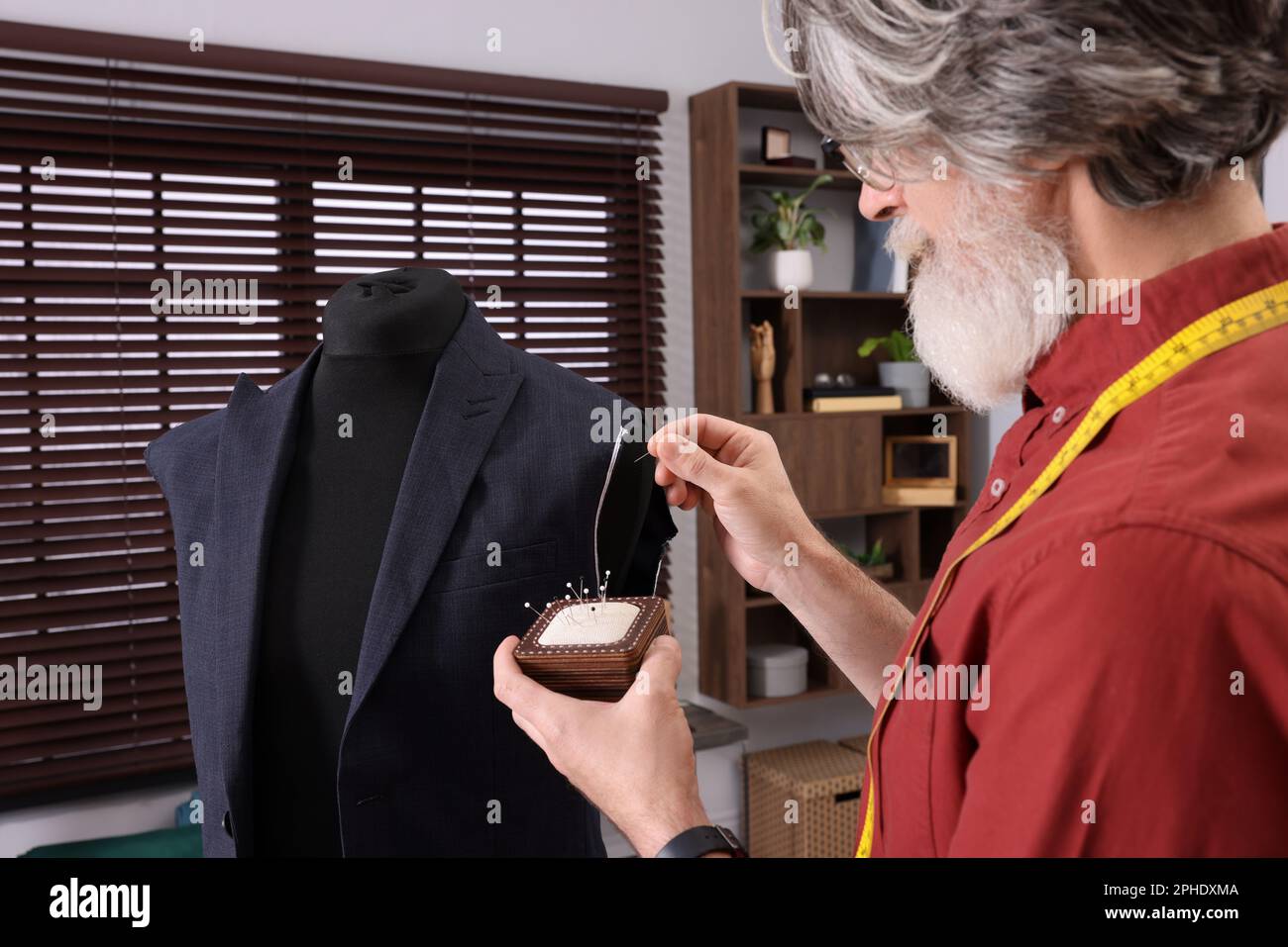 Professional tailor with pin cushion working in atelier Stock Photo - Alamy