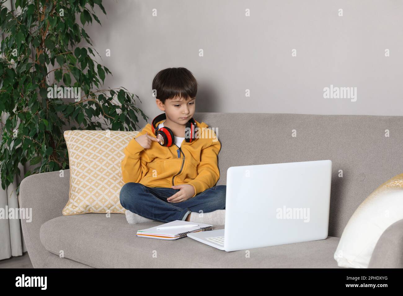 Cute little boy with modern laptop studying online at home. E-learning ...