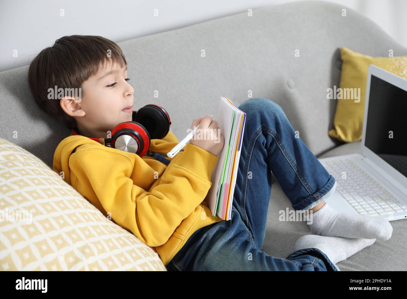 Cute little boy with modern laptop studying online at home. E-learning ...
