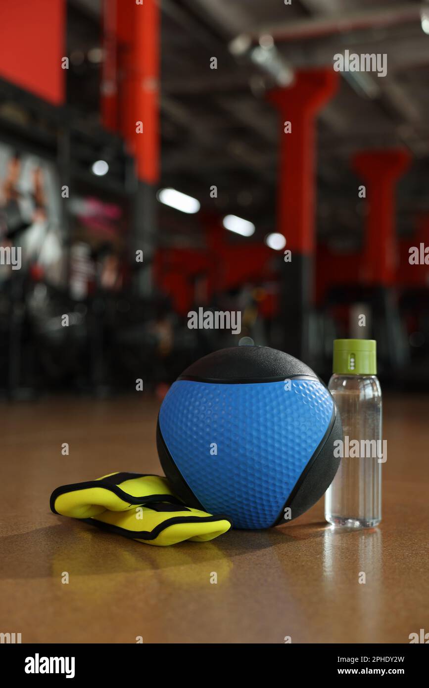 Medicine ball, bottle and ankle weights on floor in gym Stock Photo - Alamy