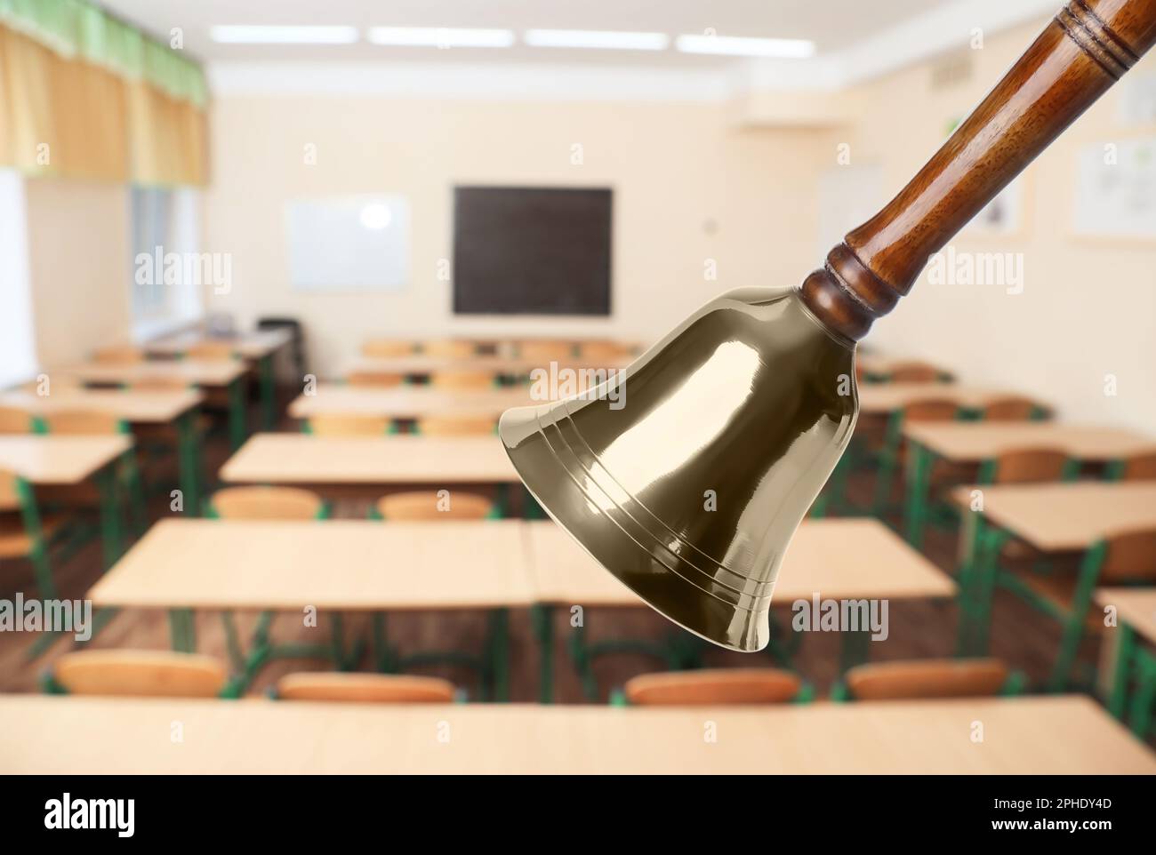 Golden school bell with wooden handle and blurred view of empty ...