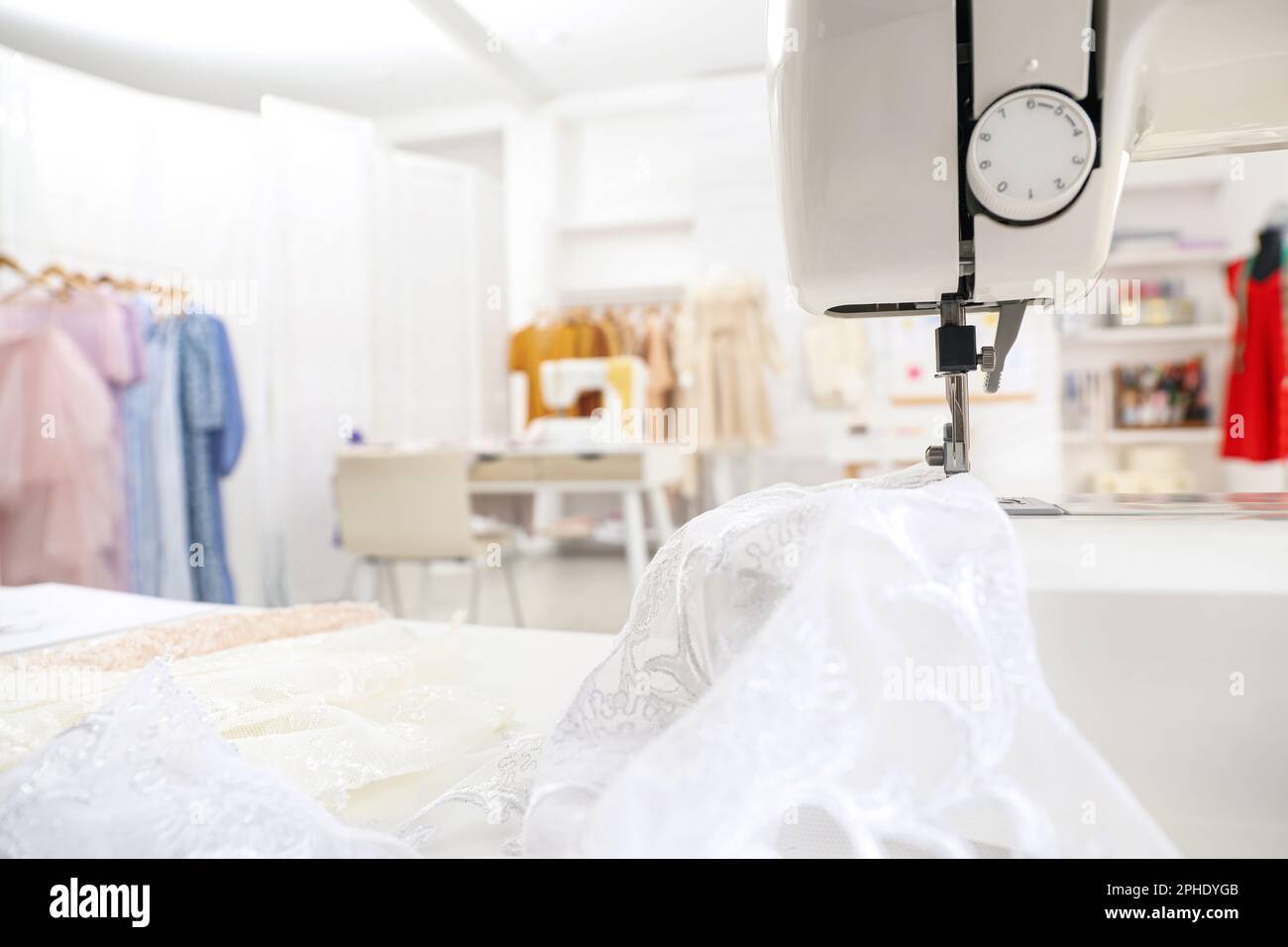 Modern sewing machine with fabric in dressmaking workshop, closeup ...