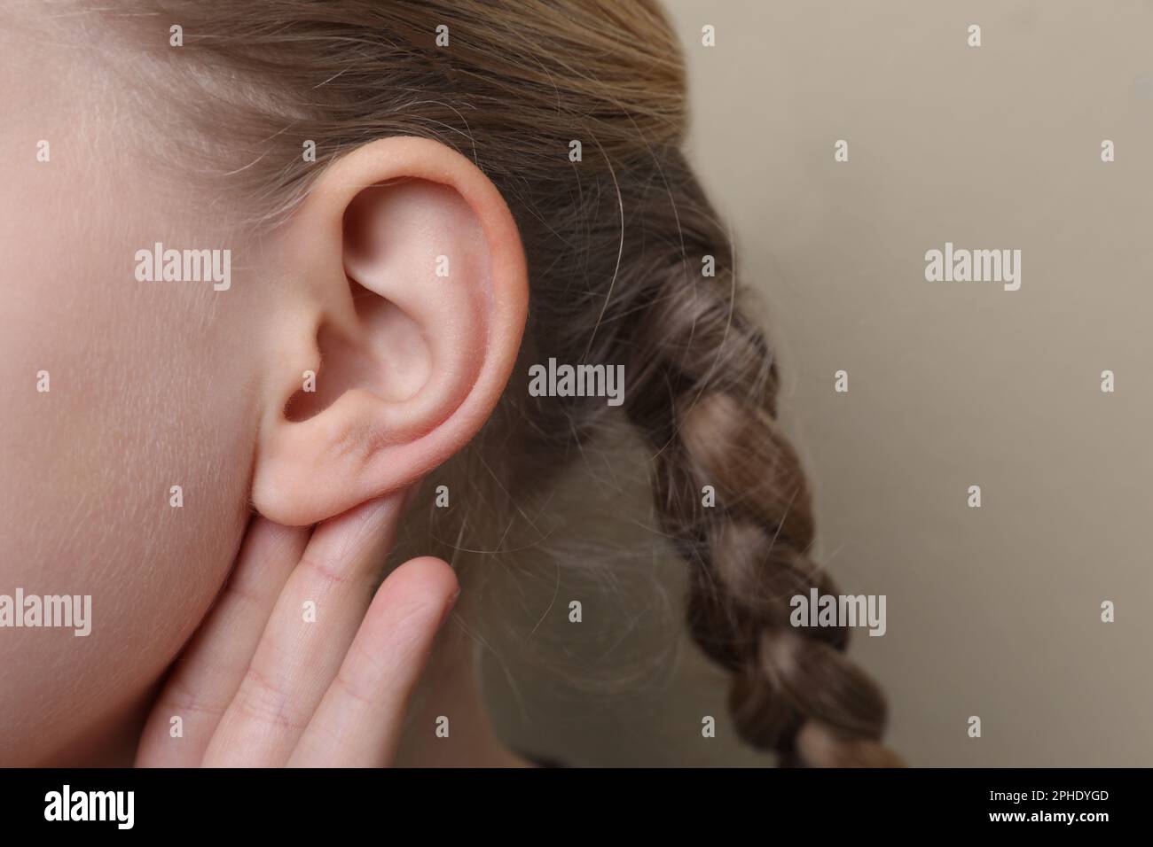 Cute little girl showing hand to ear gesture on beige background ...