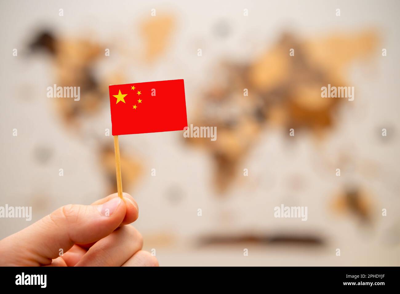 China flag in mans hand on the wooden world map background. Global ...