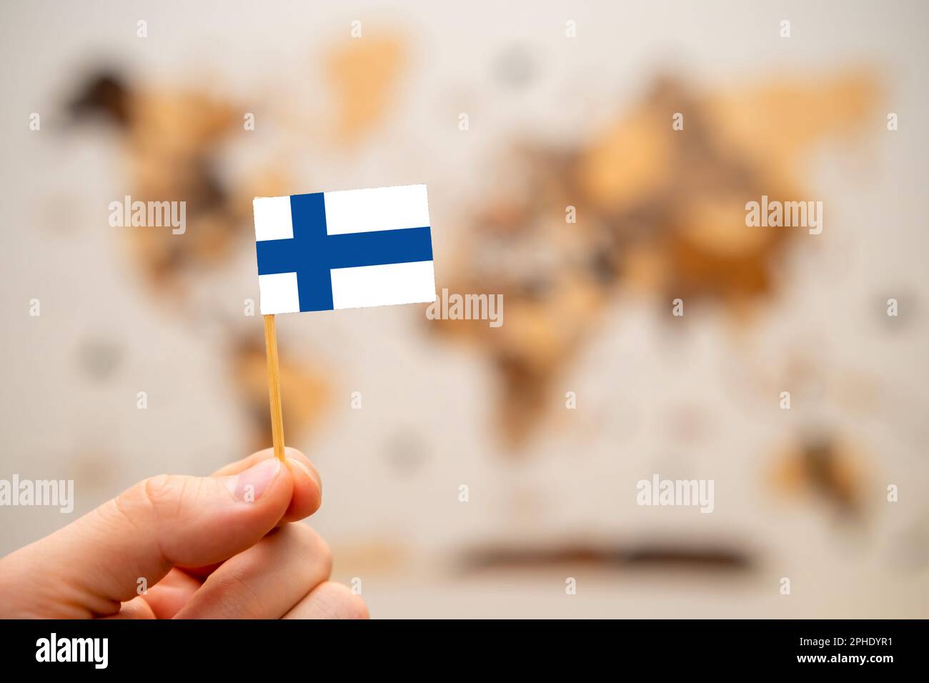 Finland flag in mans hand on the wooden world map background. Global ...