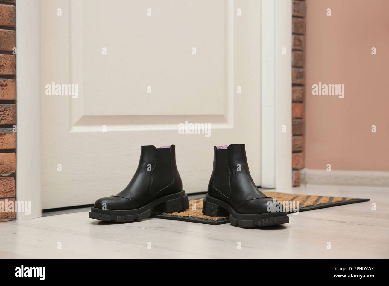 Stylish shoes on door mat in hall Stock Photo - Alamy
