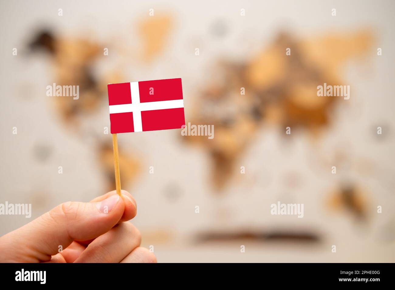 Denmark flag in mans hand on the wooden world map background. Global ...